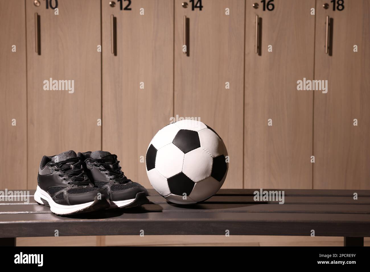 Soccer ball and sneakers on wooden bench in locker room Stock Photo - Alamy