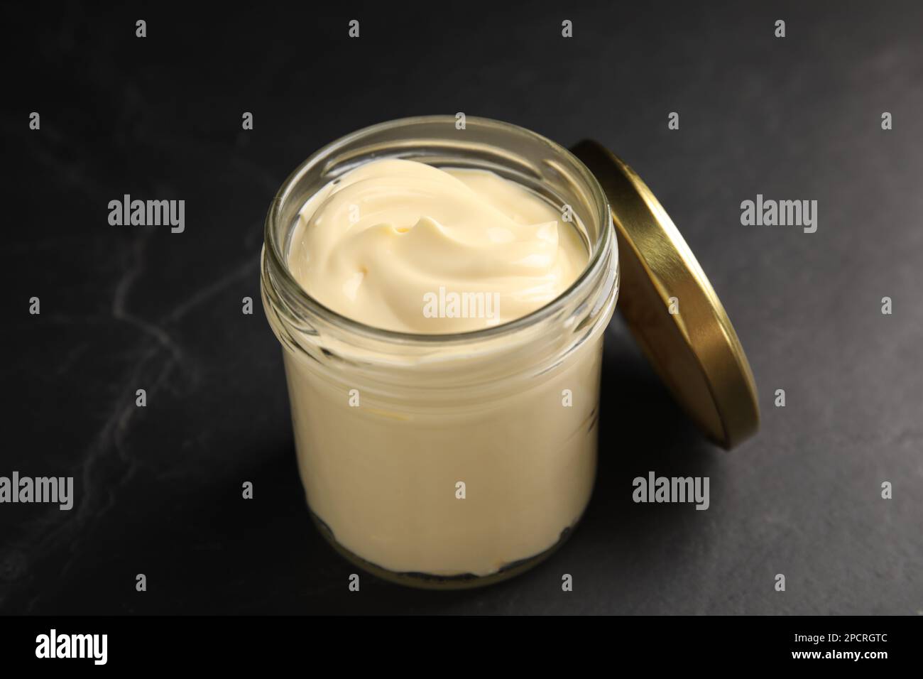 Jar of delicious mayonnaise and lid on black table Stock Photo - Alamy