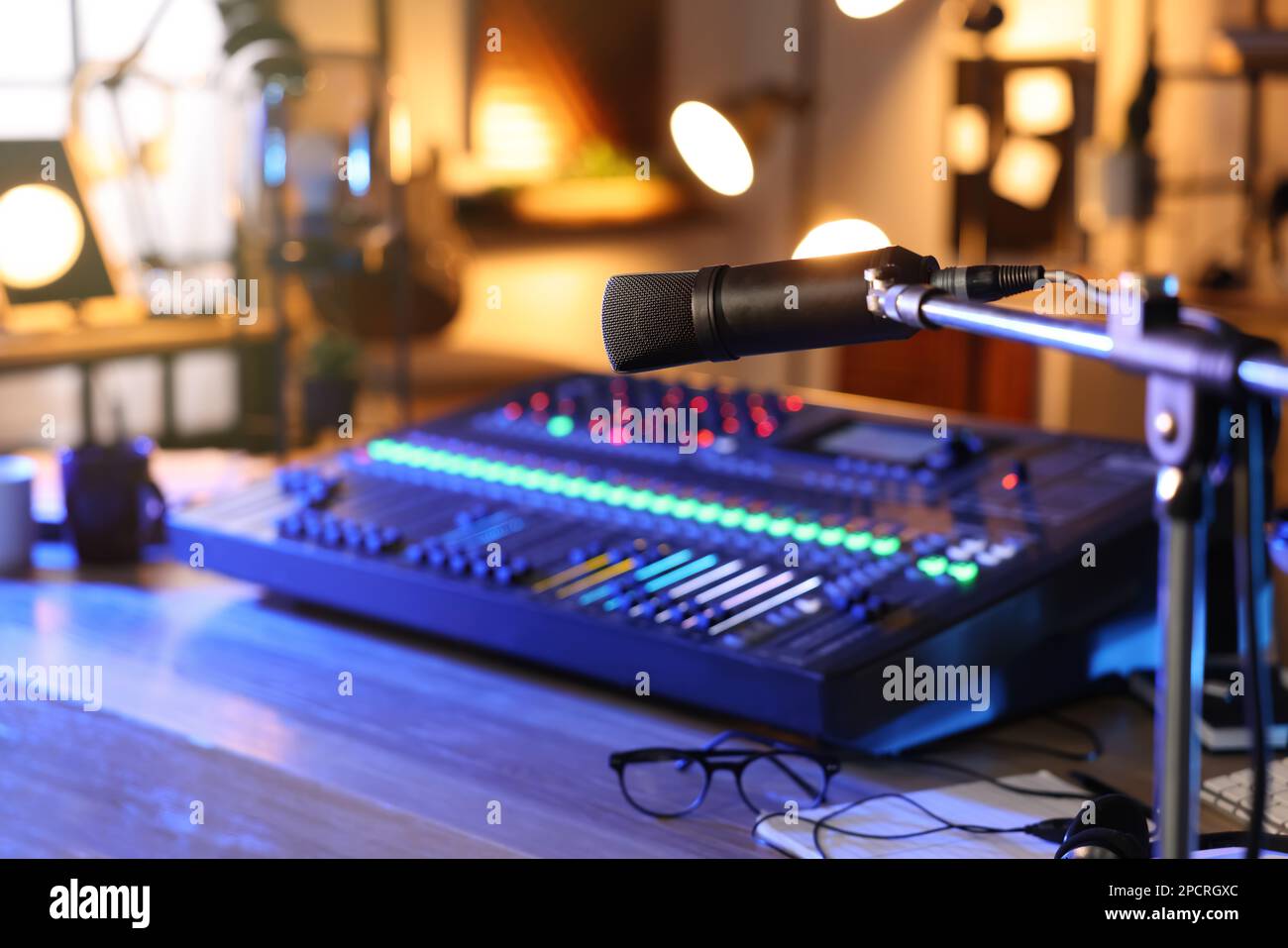Microphone near table with professional mixing console in radio studio ...