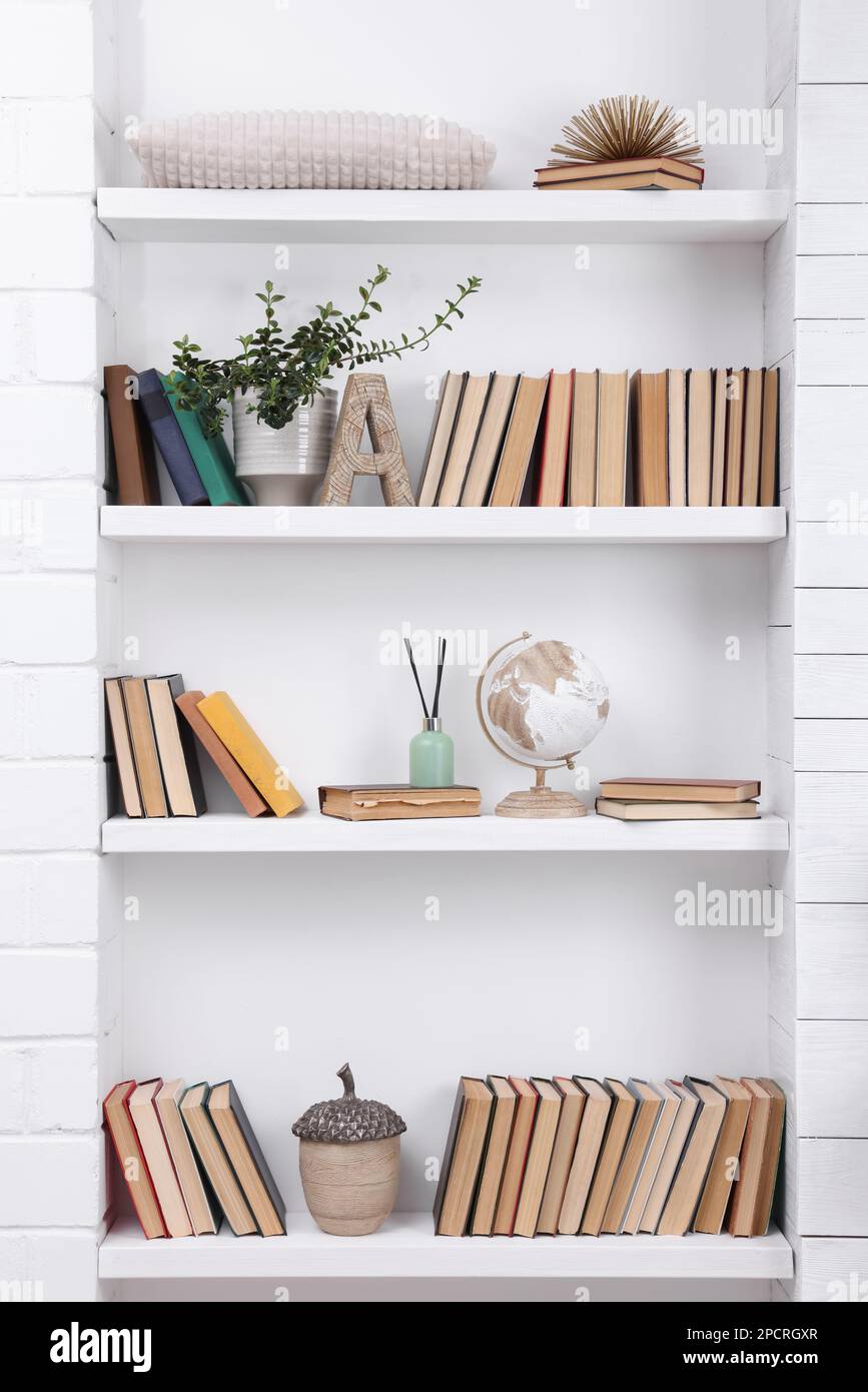 Collection of books and decor elements on shelves indoors Stock Photo ...