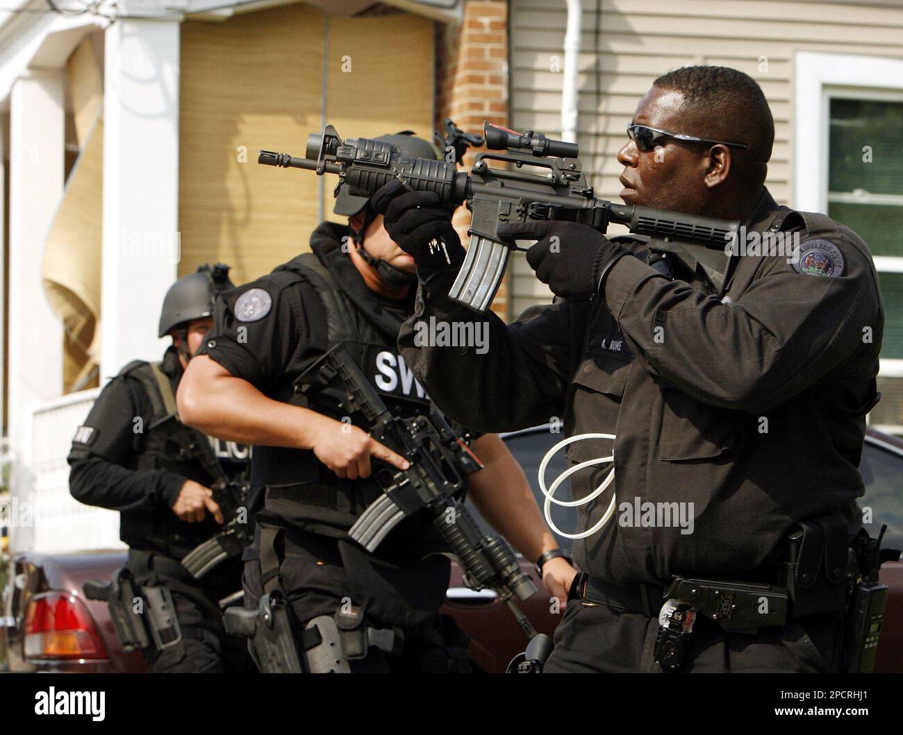A New Orleans Police SWAT officer takes aim as they serve a warrant in ...