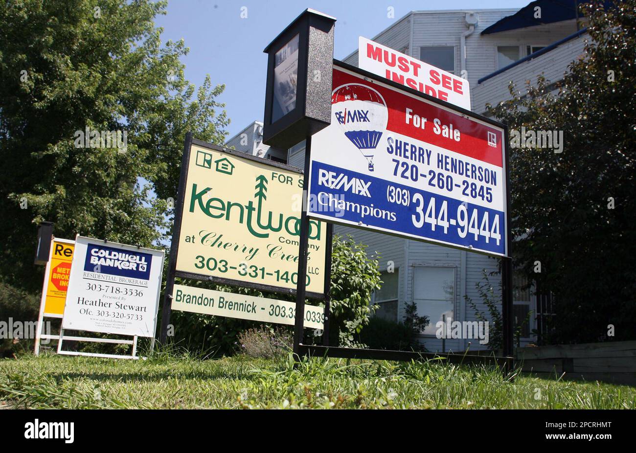 Signs from realtors for available units crowd the small patch of lawn ...