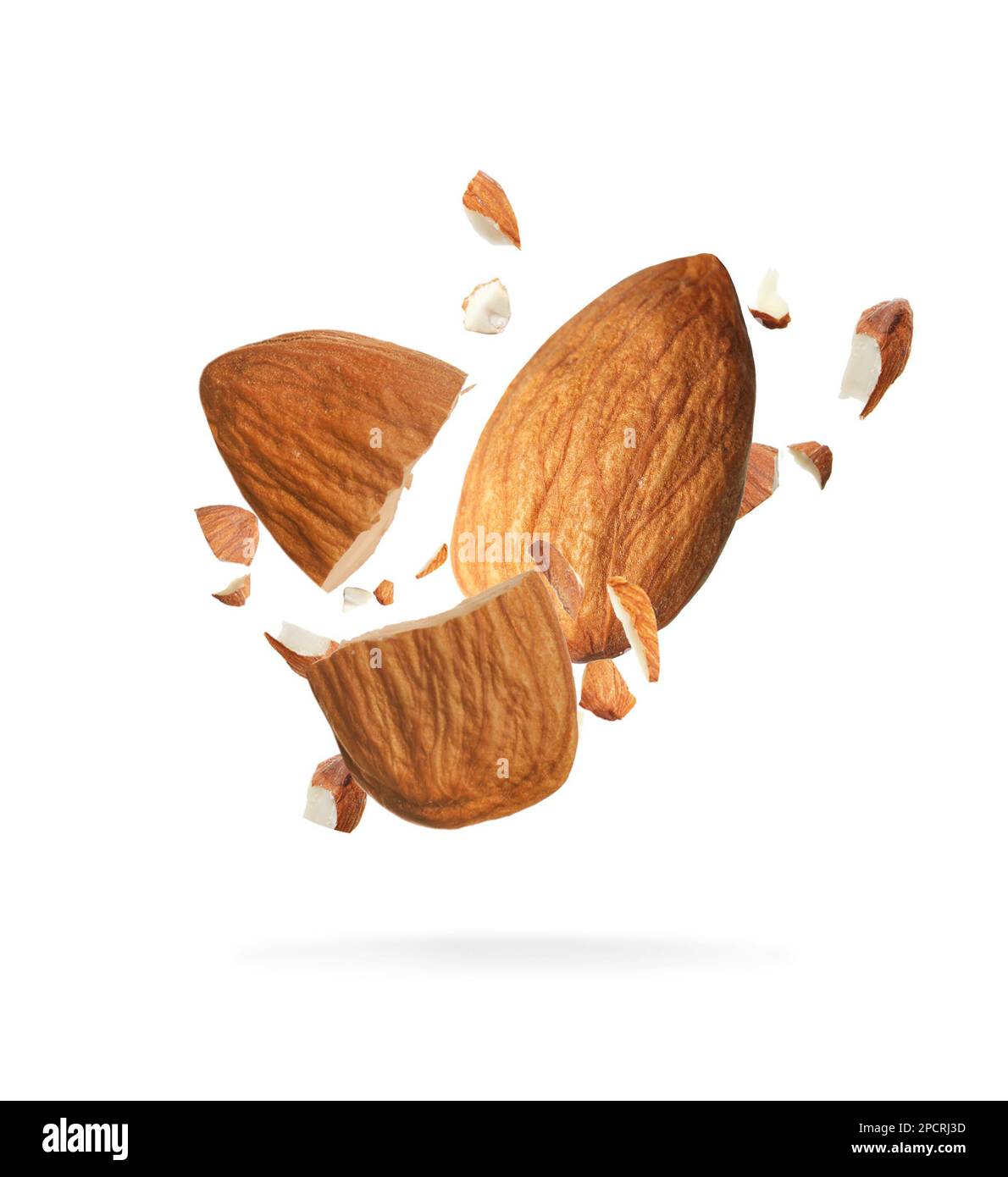 Pieces of tasty almonds falling on white background Stock Photo - Alamy