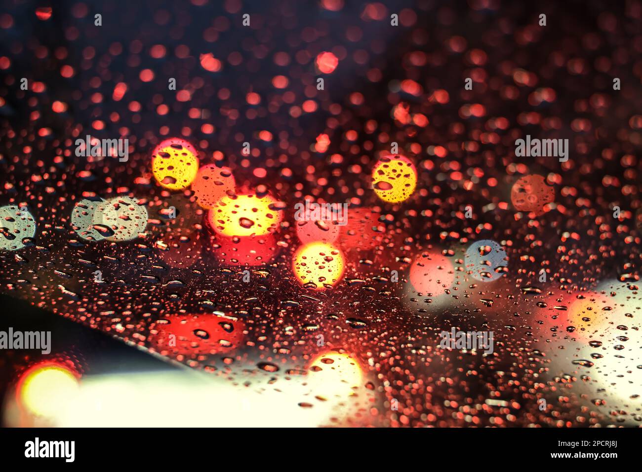 Blurred view of road through wet car window at night. Bokeh effect ...