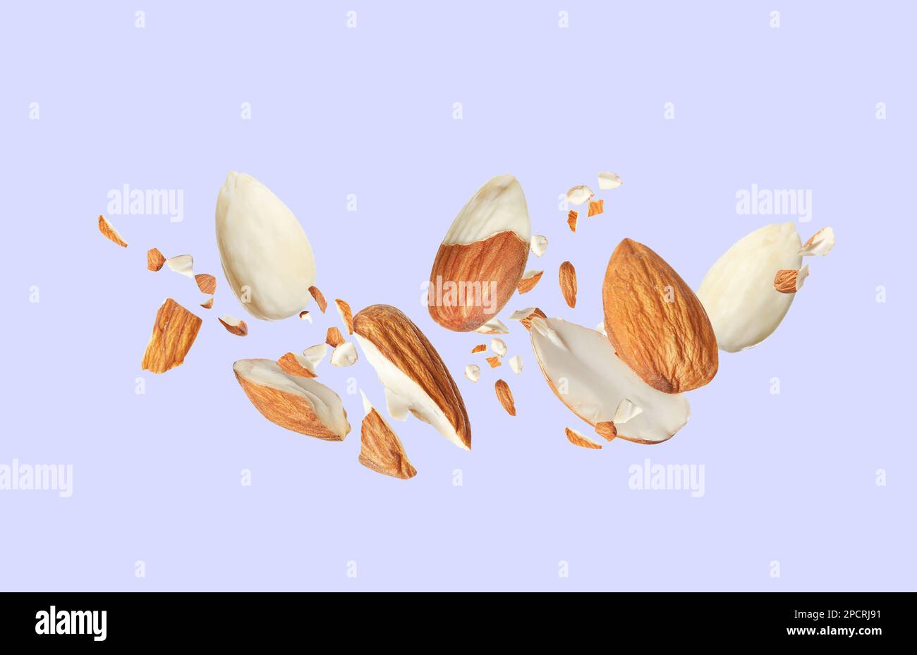 Pieces of tasty almonds falling on light grey background Stock Photo ...