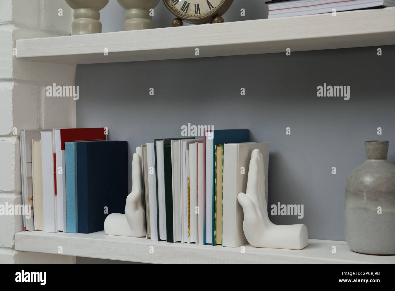 Hand shaped bookends with books on shelf indoors. Interior design Stock ...