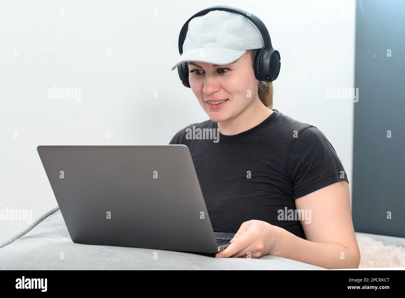 Busy young woman in headphones working on laptop, making video call and ...