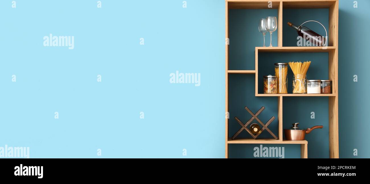 Wooden shelving unit with products near blue wall in kitchen. Banner ...