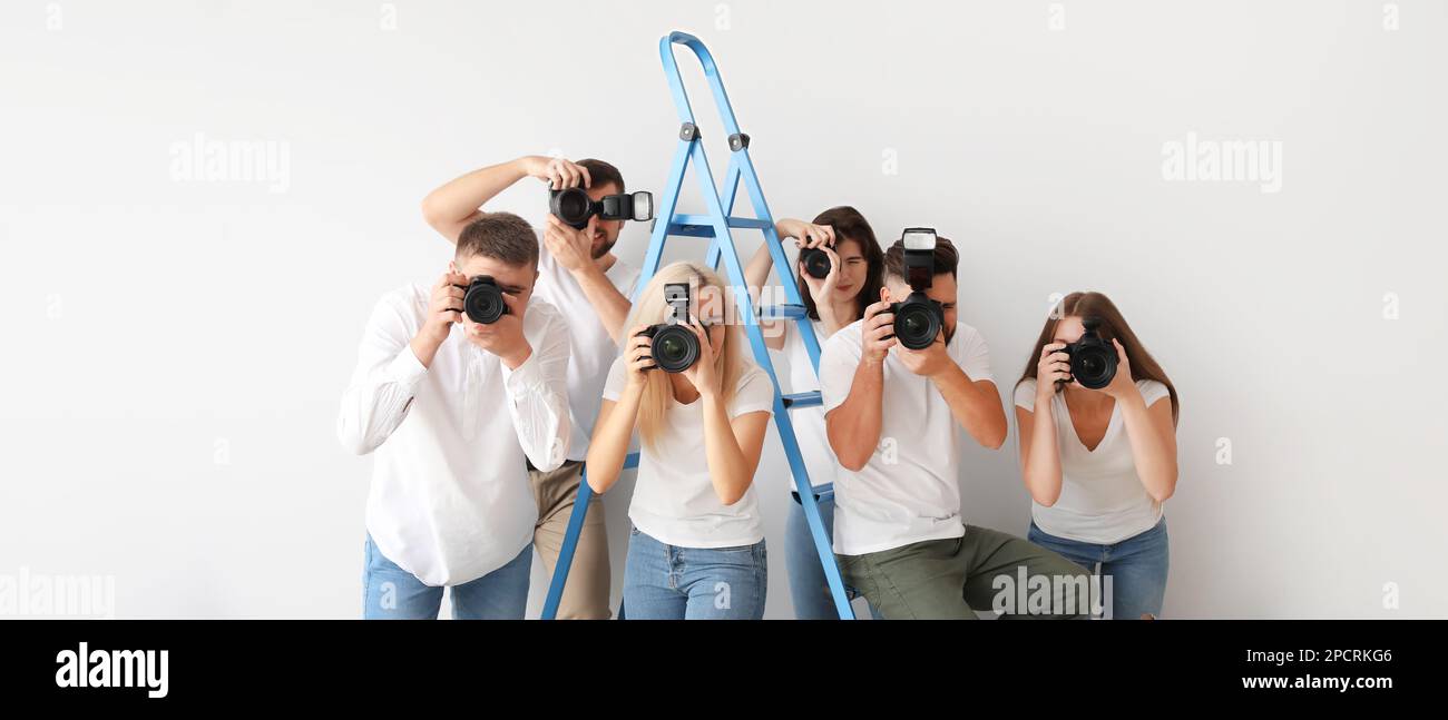 Group of young photographers with photo cameras on light background ...