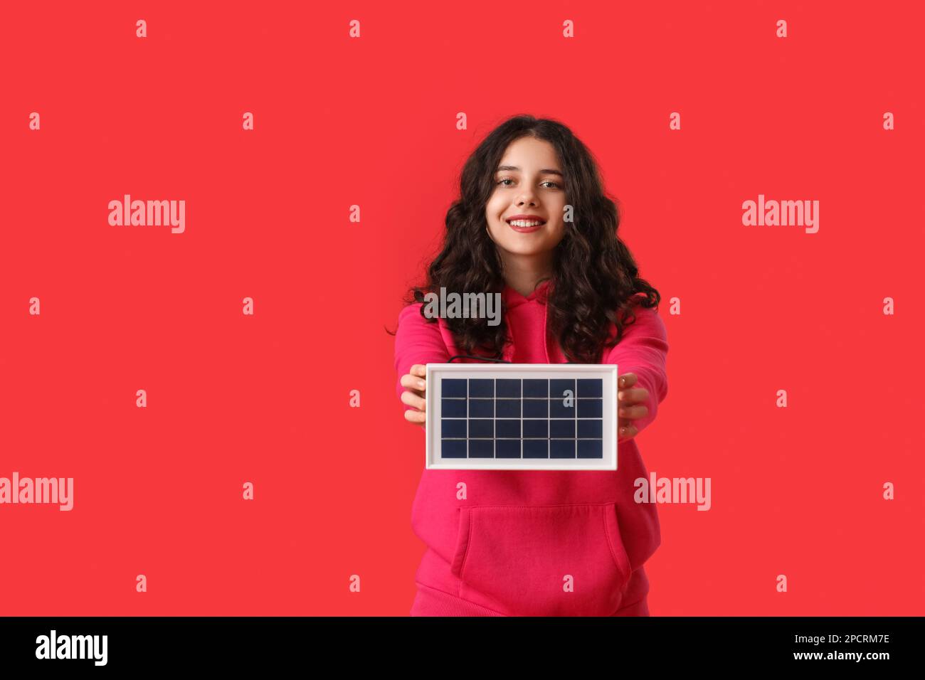 Teenage girl with portable solar panel on red background Stock Photo ...