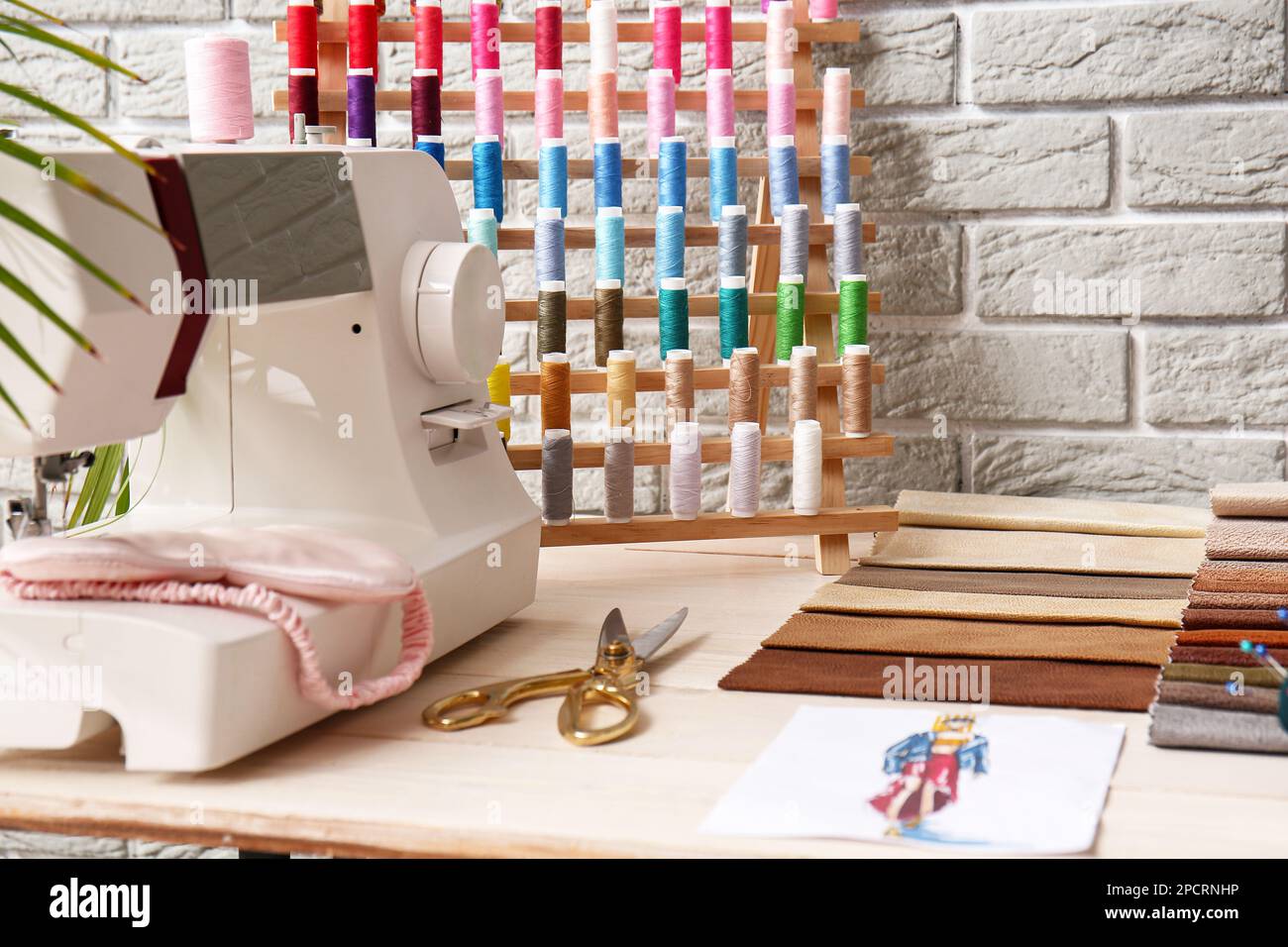 Tailor's workplace with sewing machine, thread spools and fabric ...