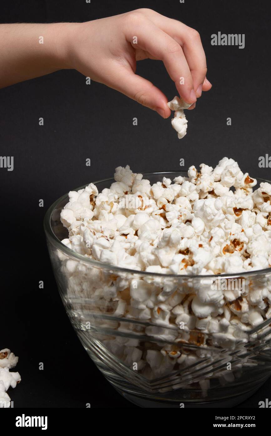 A child's hand reaches for popcorn in a glass bowl Stock Photo - Alamy
