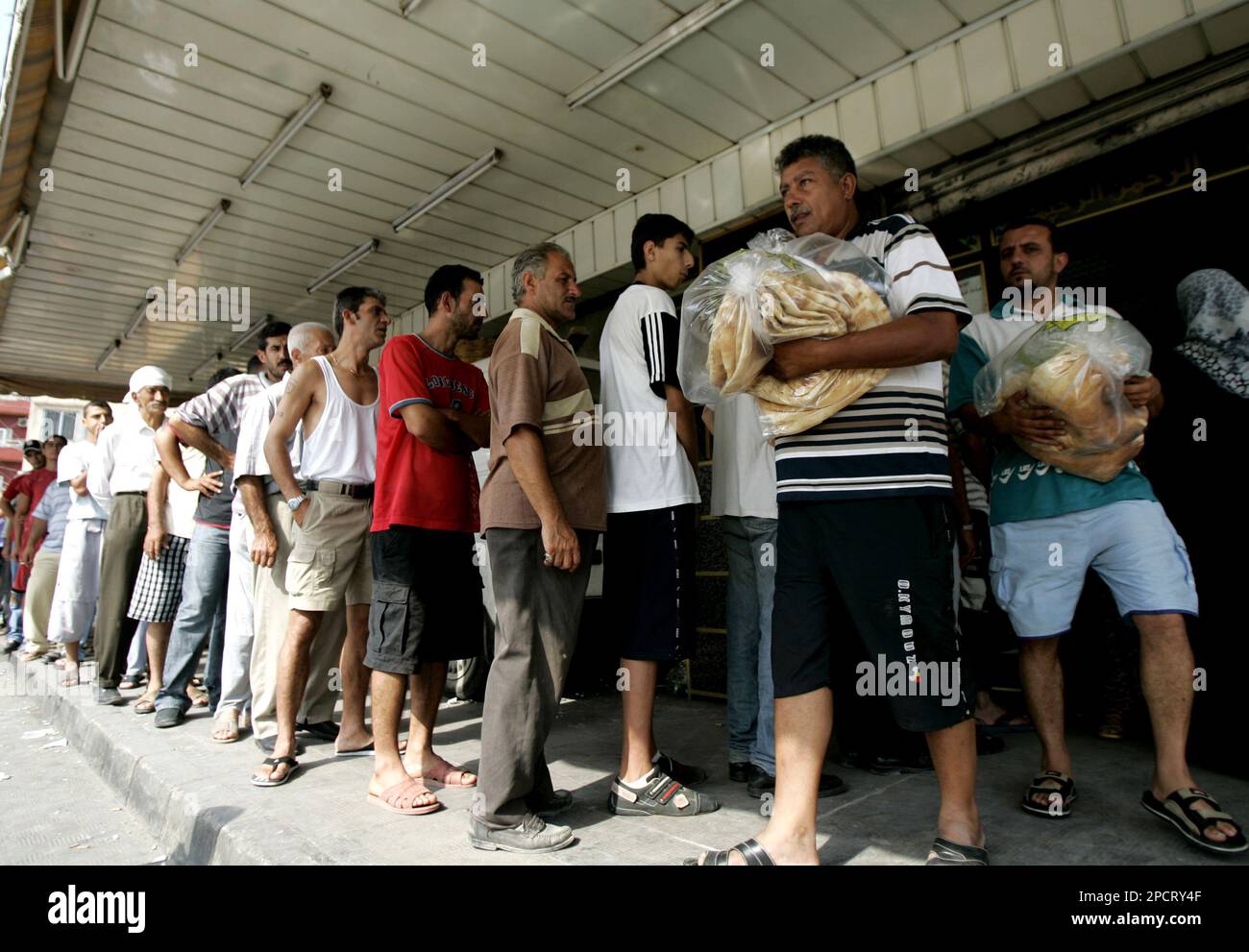 Lebanese men queue for bread in front of a bakery at the southern ...