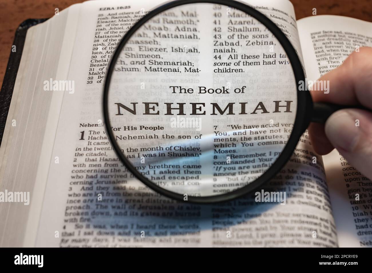 A closeup of a person holding a magnifier and reading the book of ...