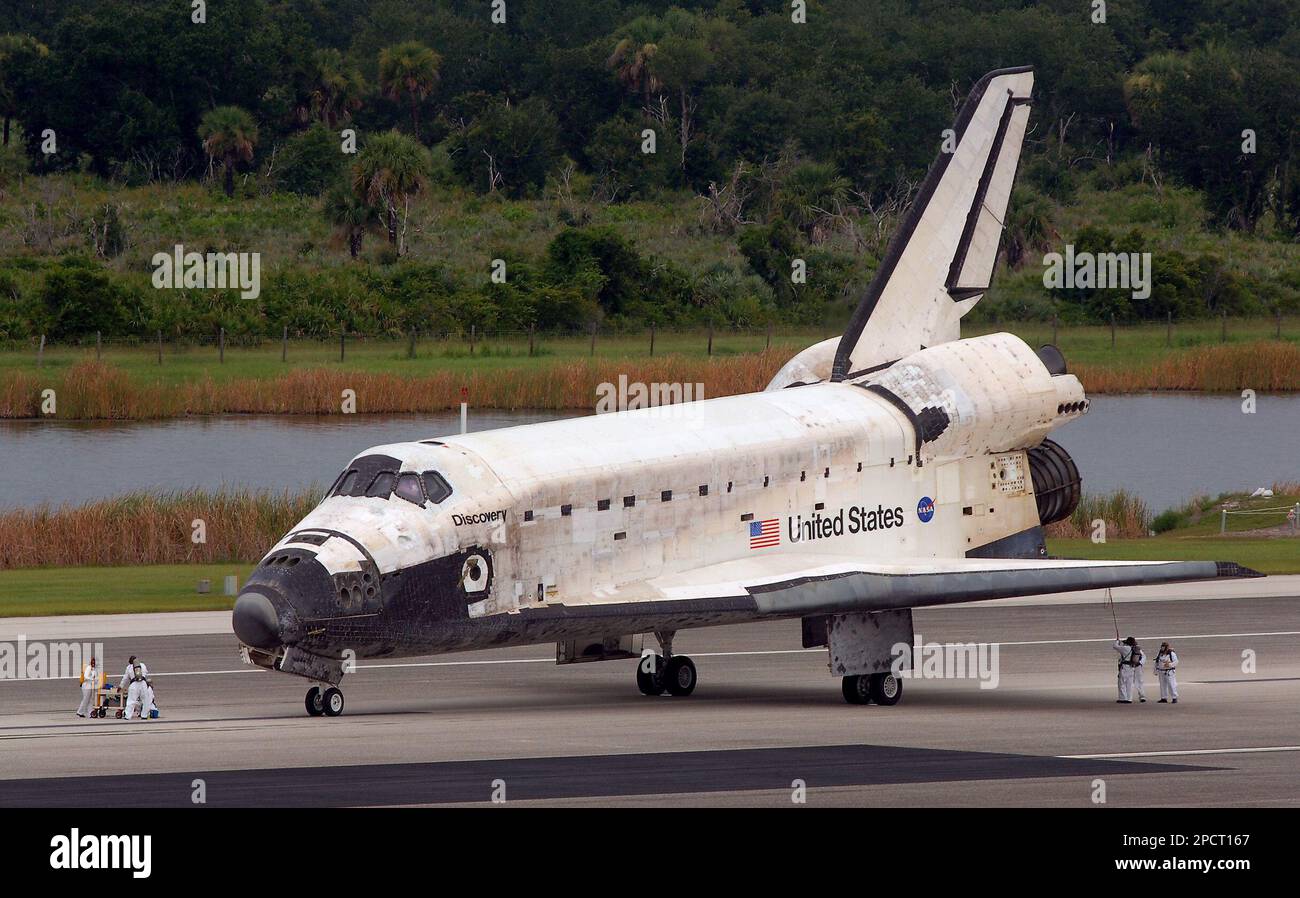 Ground crew members check the Space Shuttle Discovery after its landing ...