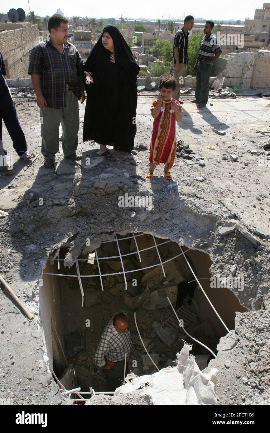 Local residents look at the damage from a rocket attack on their home ...