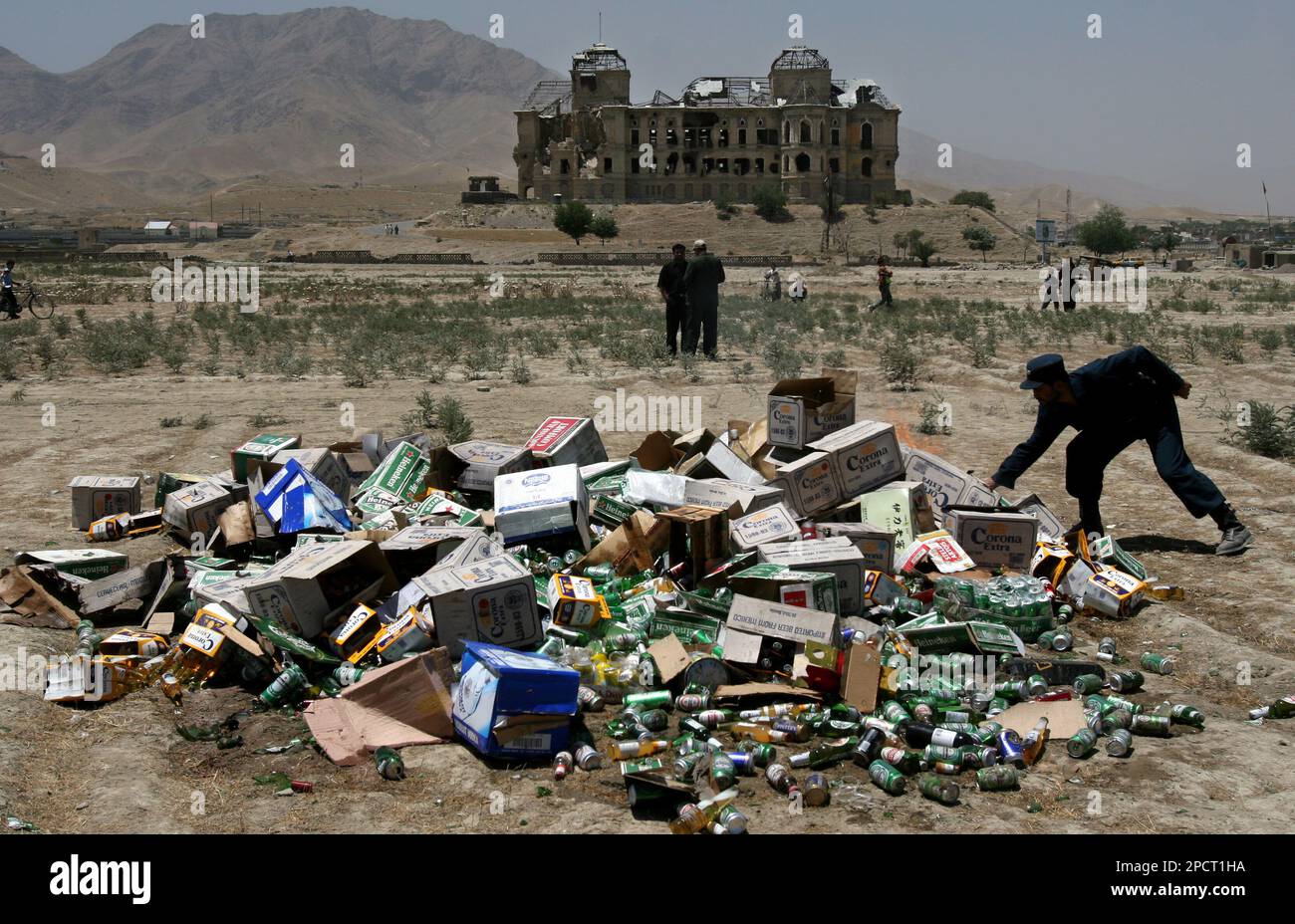 An Afghan policeman tries to burn alcoholic drinks in a Kabul park in ...