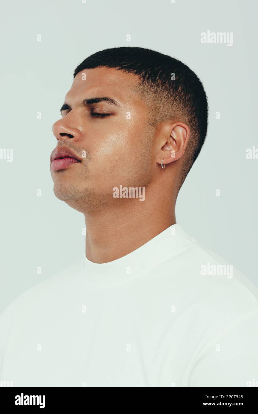 Youthful man standing in a studio with closed eyes, showing his ...