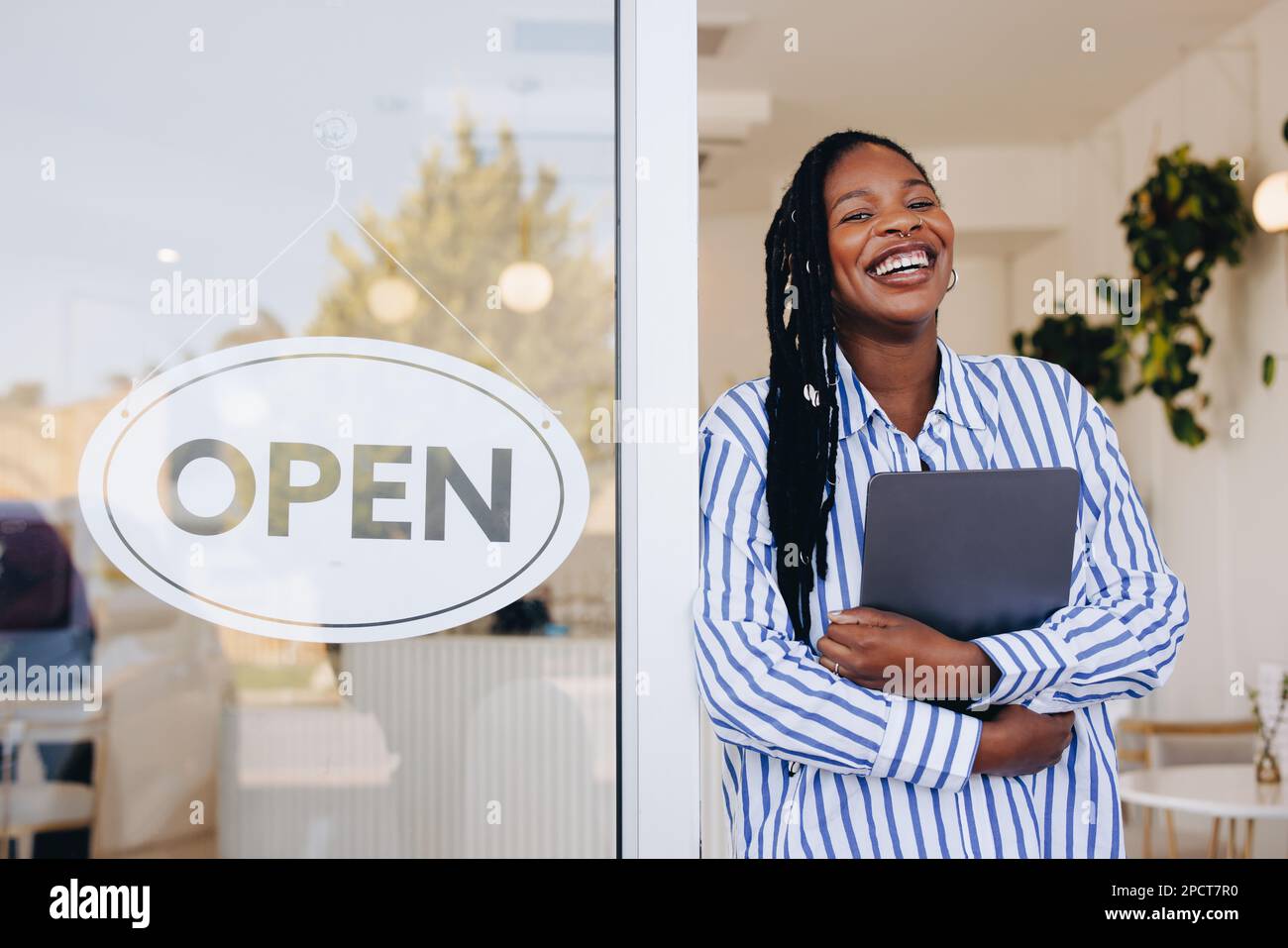 Cheerful young restaurant owner standing next to an open sign at the ...