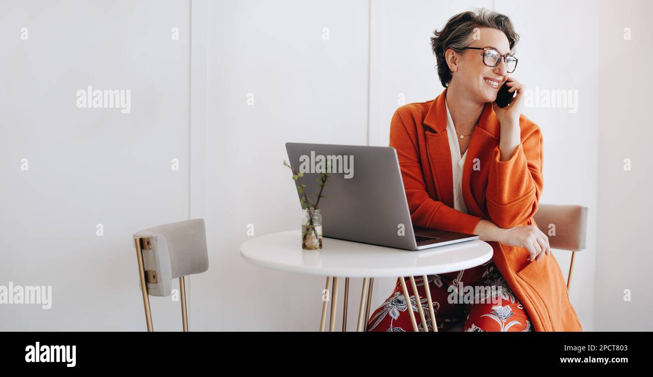 Successful businesswoman speaking to a client on the phone while ...