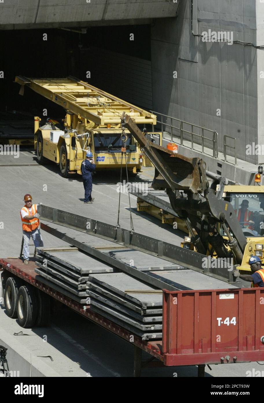 Workers stack ceiling panels and hardware that were removed from one of ...