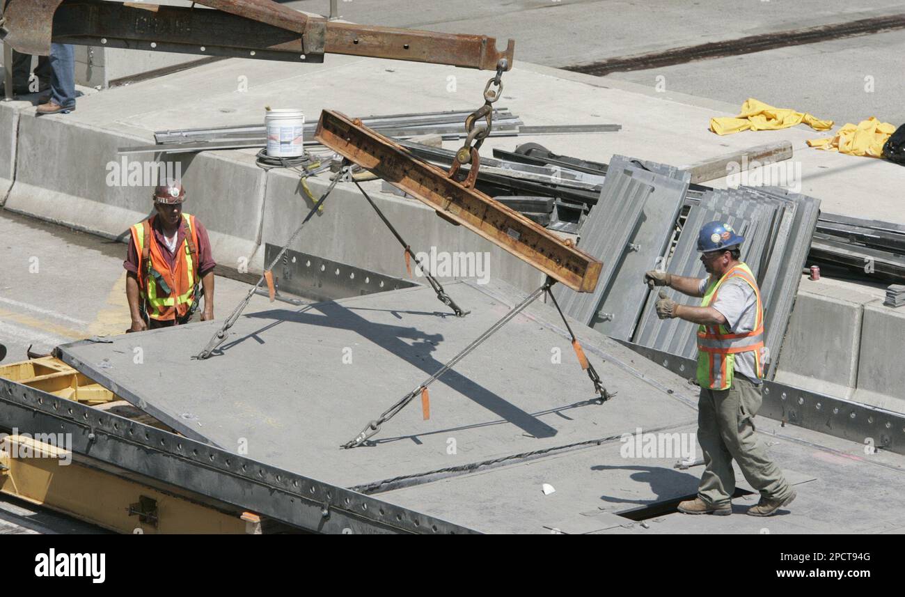 Workers guide a concrete ceiling panel as it is lifted from its ...