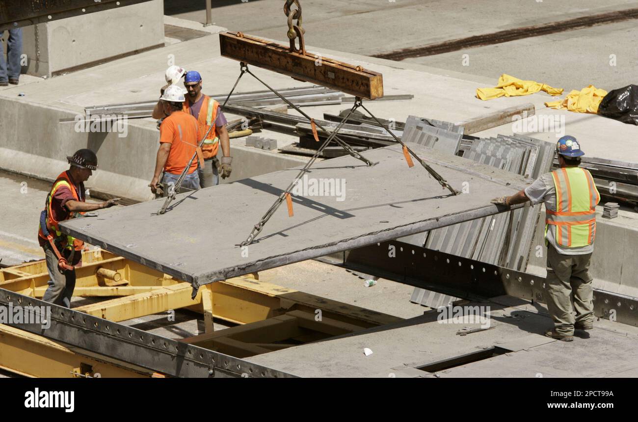 Workers guide a concrete ceiling panel from its framework after the ...