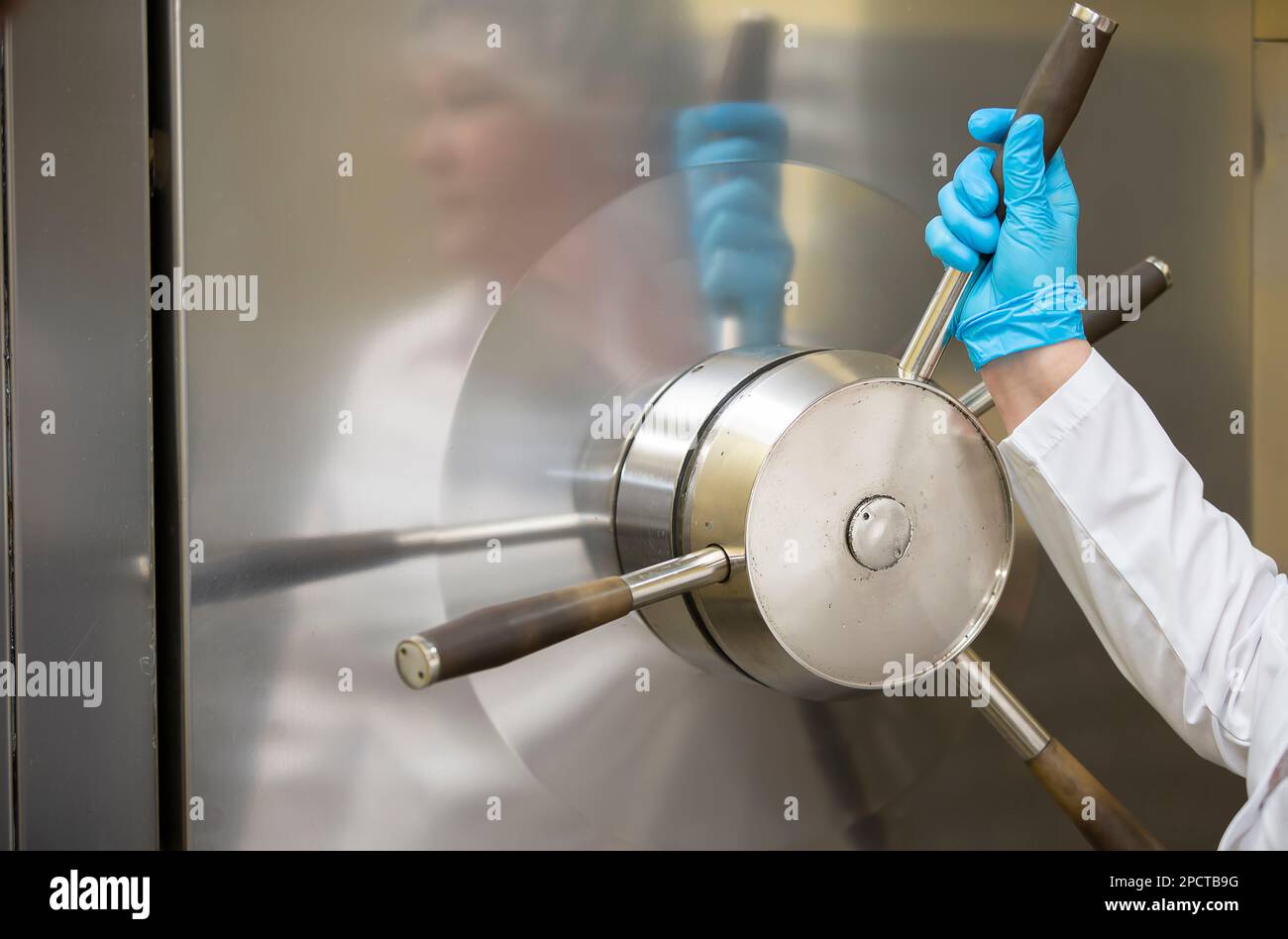 A worker's hand turns a valve in a pharmaceutical or medical device ...