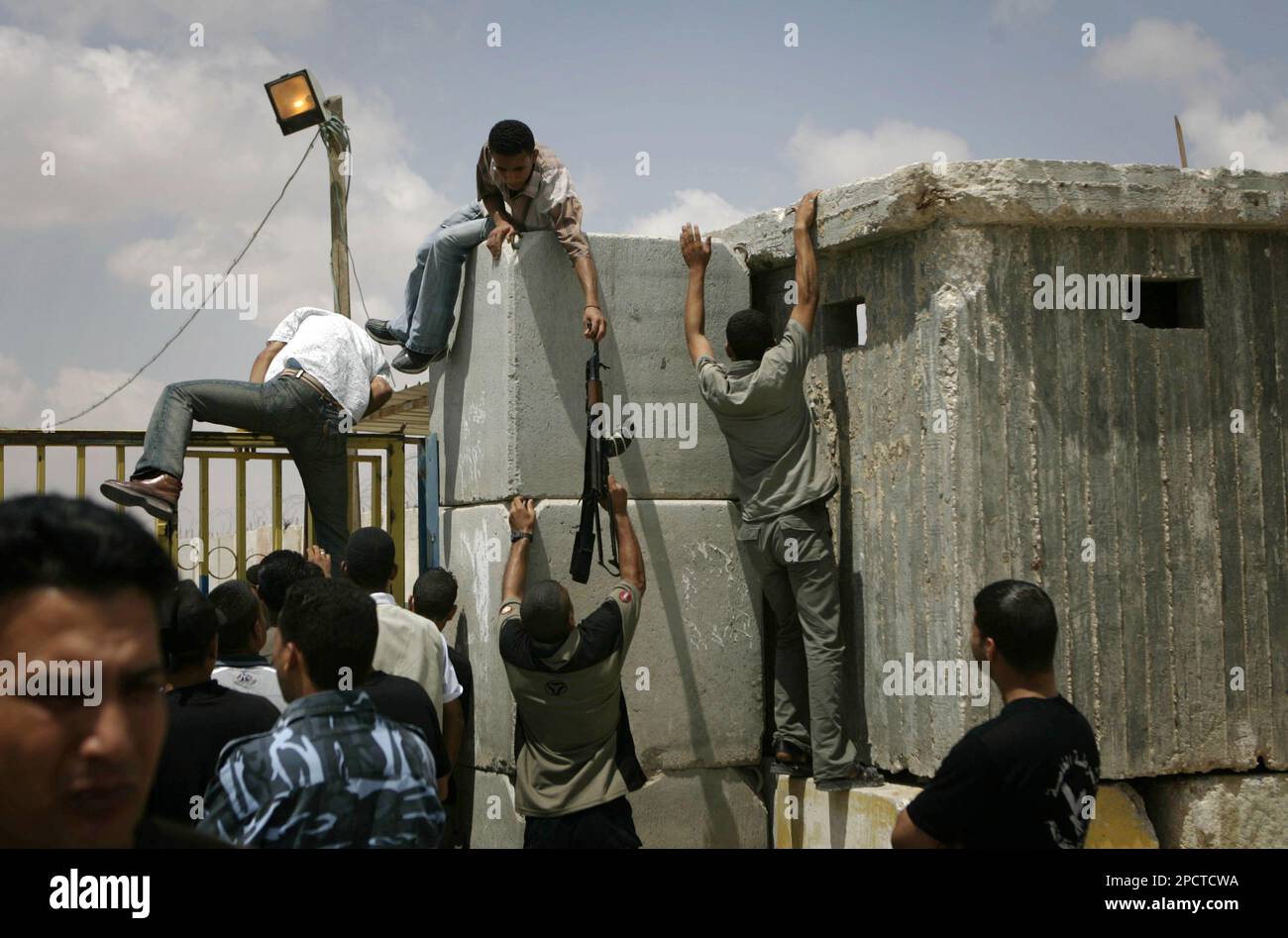 Palestinians climb the wall of the Rafah border crossing on the border ...