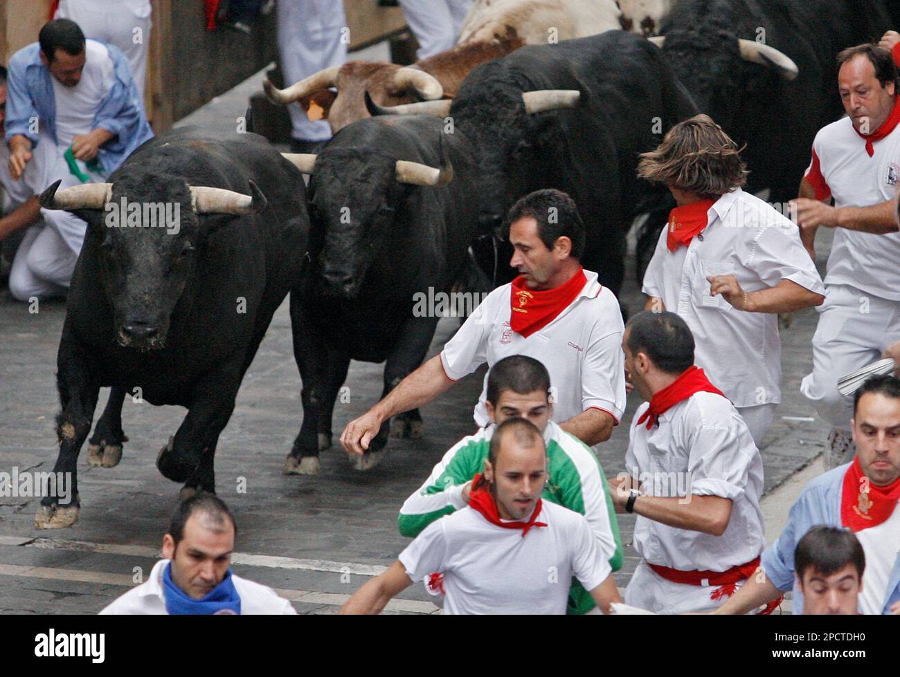 Runners are chased by a pack of fighting bulls during a bullrun through ...
