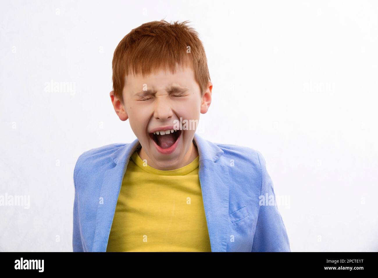 Child with an angry expression. The boy screams and closed his eyes ...