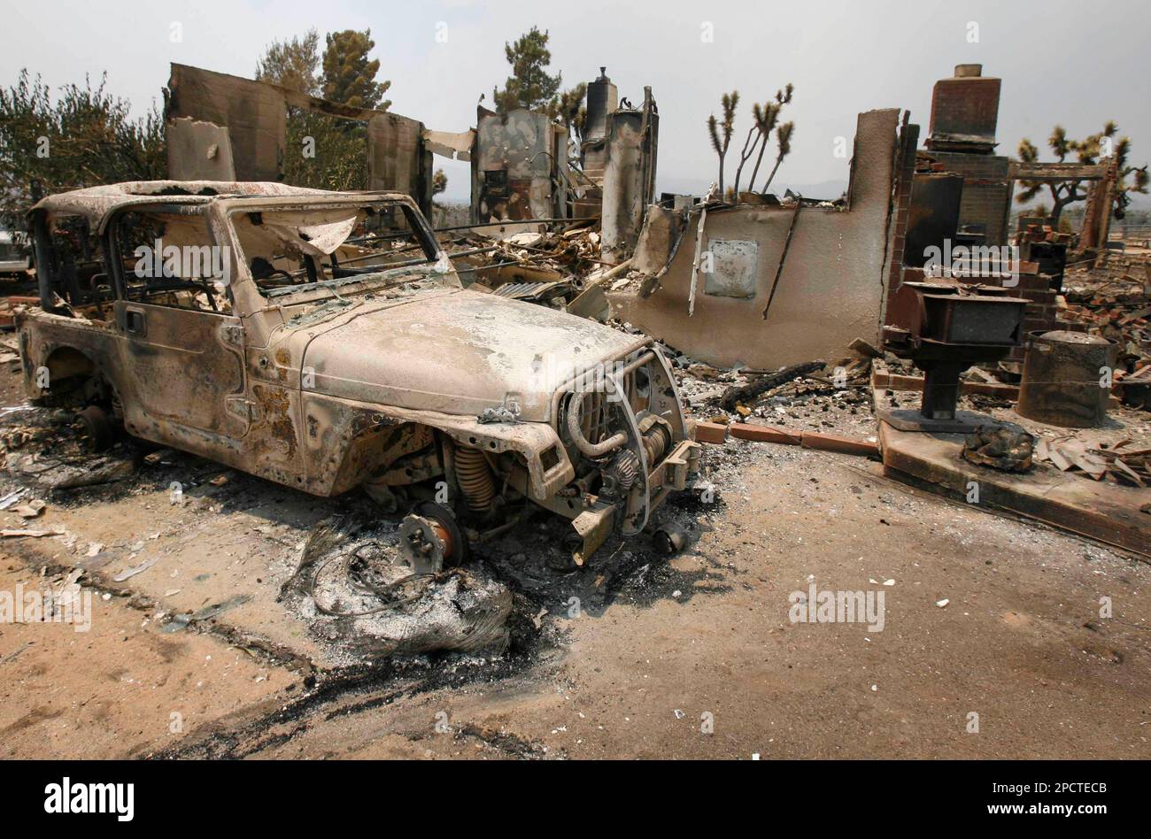 The charred remains of a car and a structure are seen after the ...