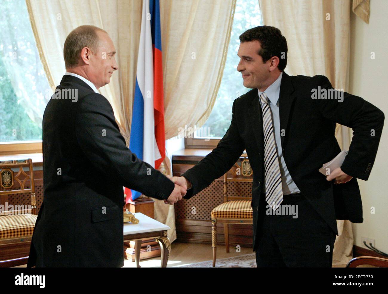 Russian President Vladimir Putin smiles as he shakes hands during an ...