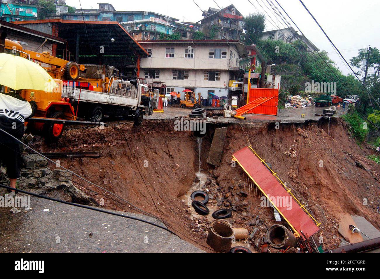 Vehicles lay precariously on the road Wednesday July 12, 2006 following a landslide in Baguio ...