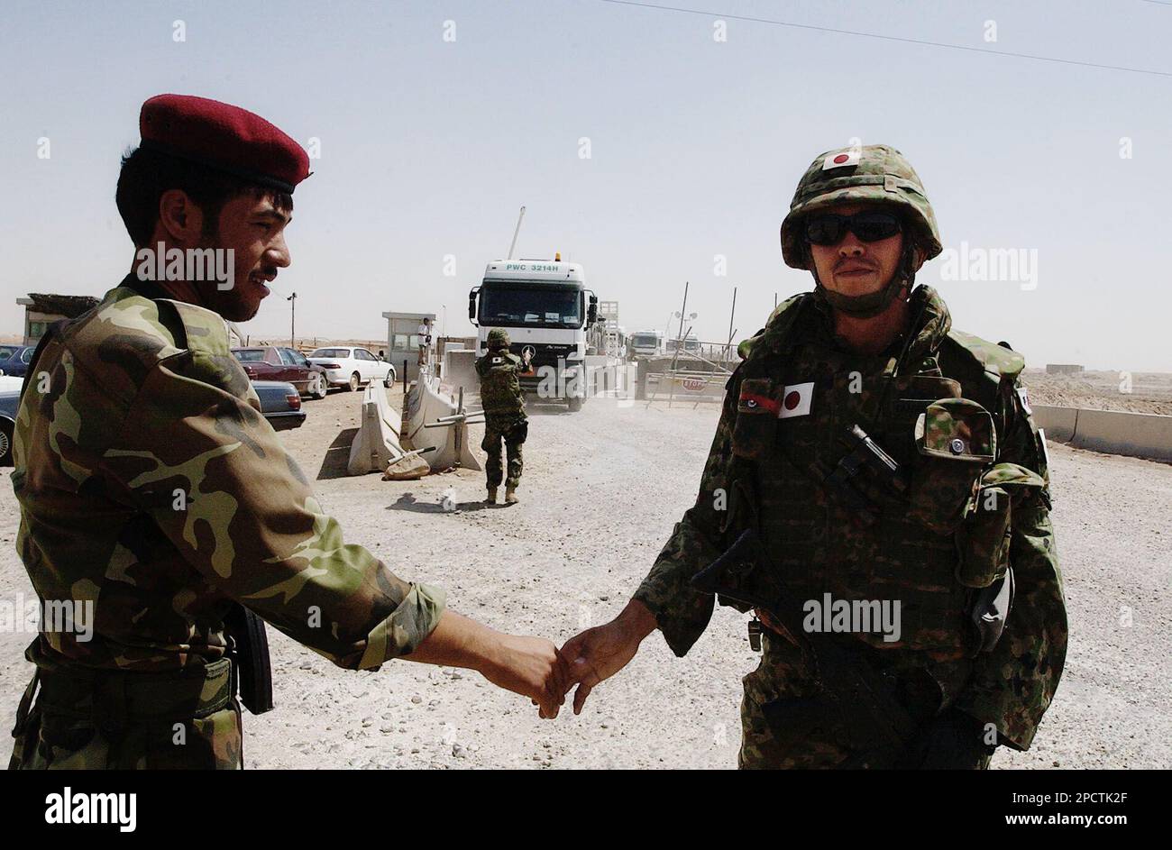 A member of the Japanese coalition forces, right, shakes hands with an ...