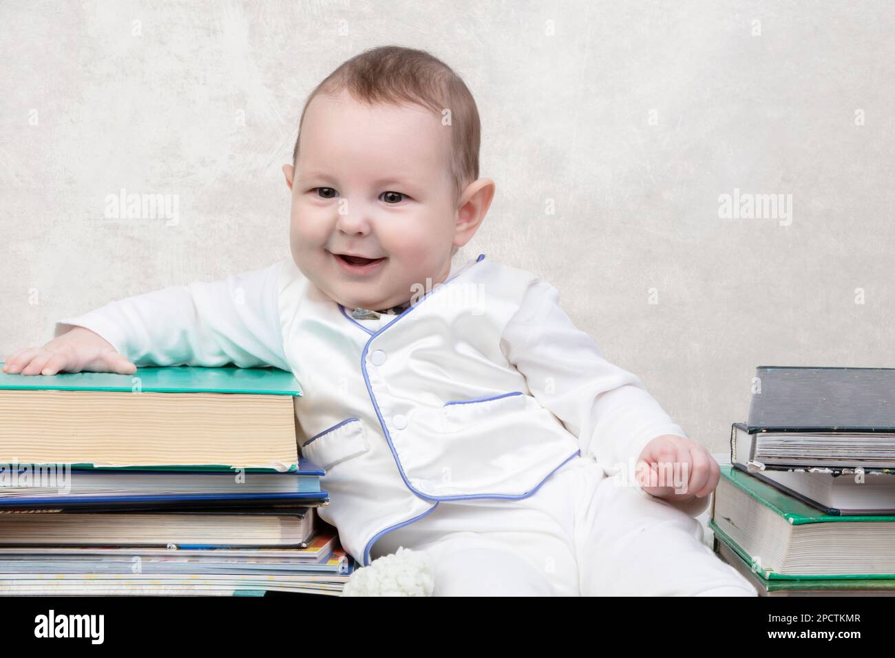Little child among books. Happy six month old baby boy in a stack of ...
