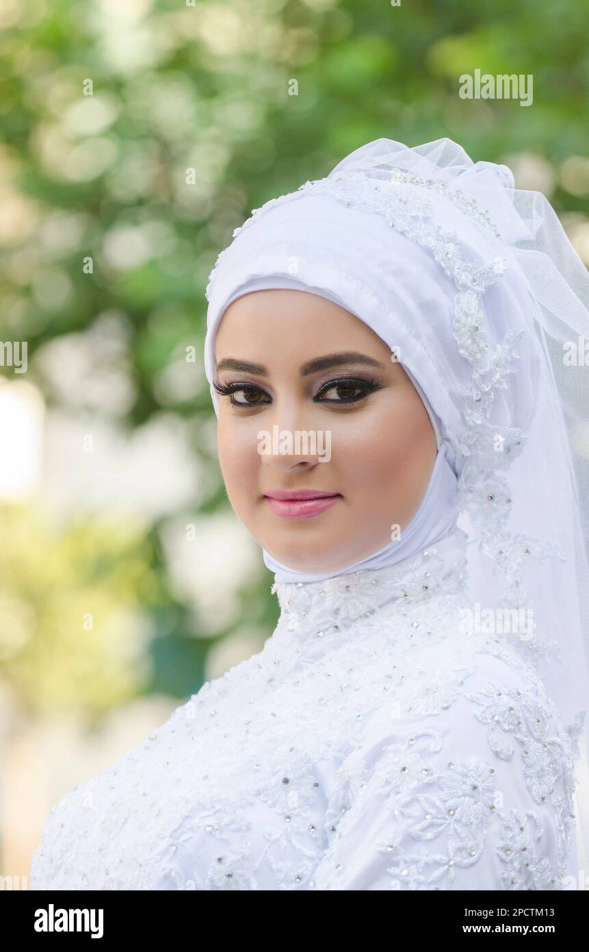 Beautiful Muslim bride in her wedding dress looking at camera outdoors ...