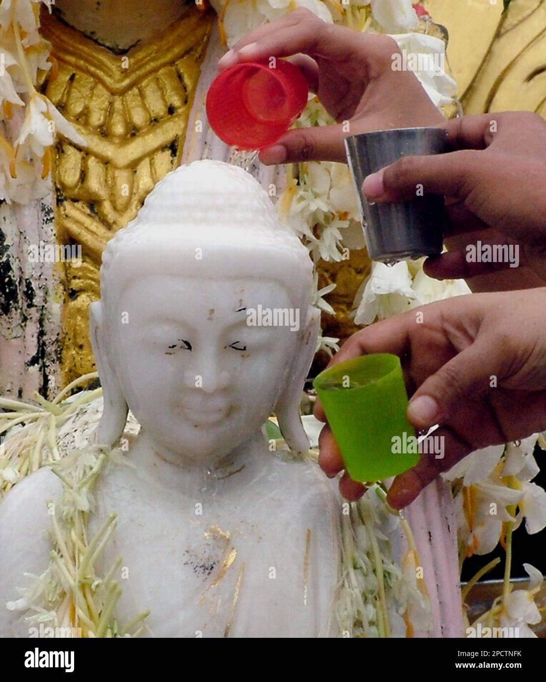 Pilgrims pouring water on a marble Buddha statue, as an act of merit ...