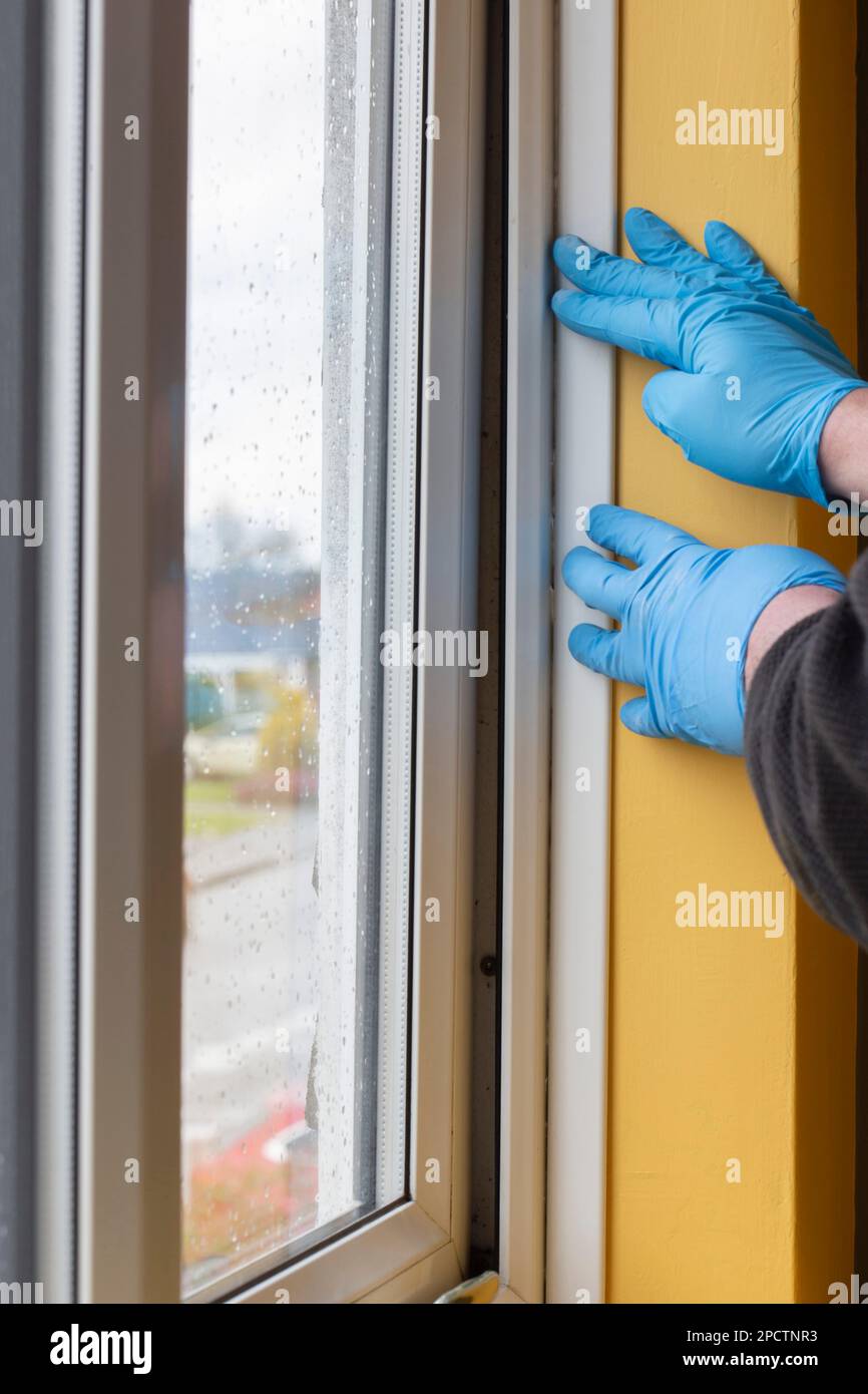Man installing plastic beading to an interior wall and window. Home DIY ...