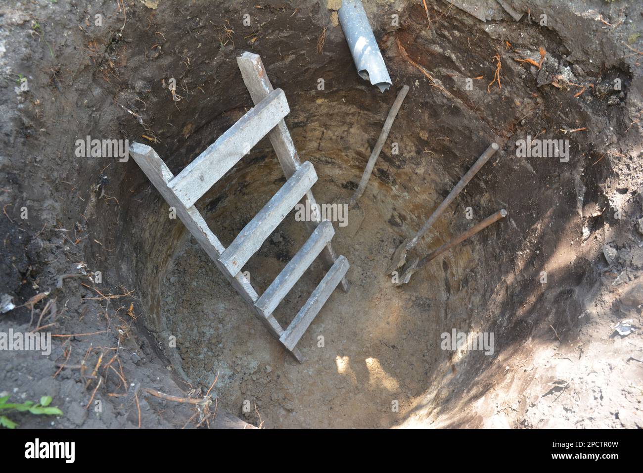 Digging a deep round hole with sewer line, drain pipe outlet for a ...