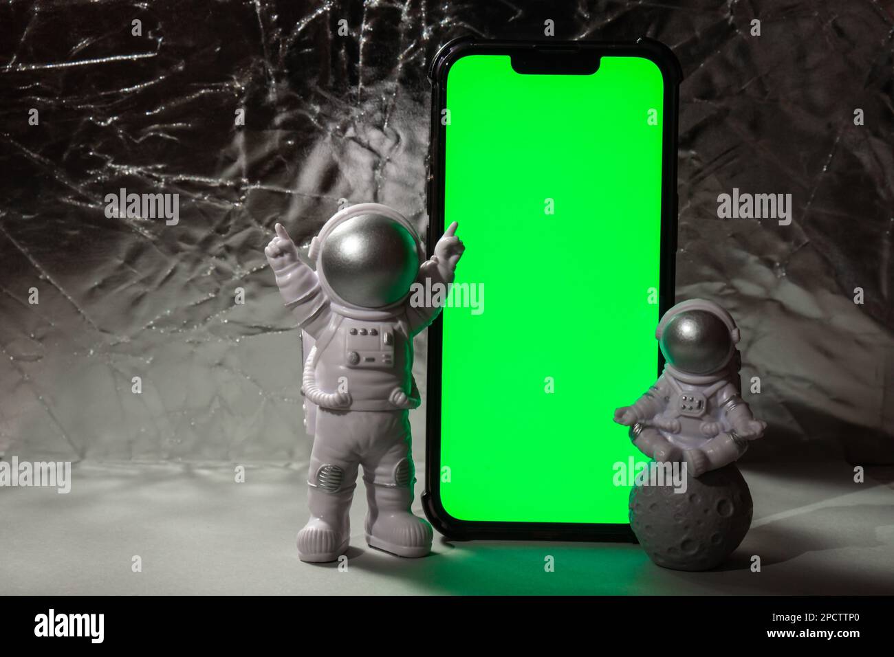Plastic toy figure astronaut with mobile phone chroma key green screen ...
