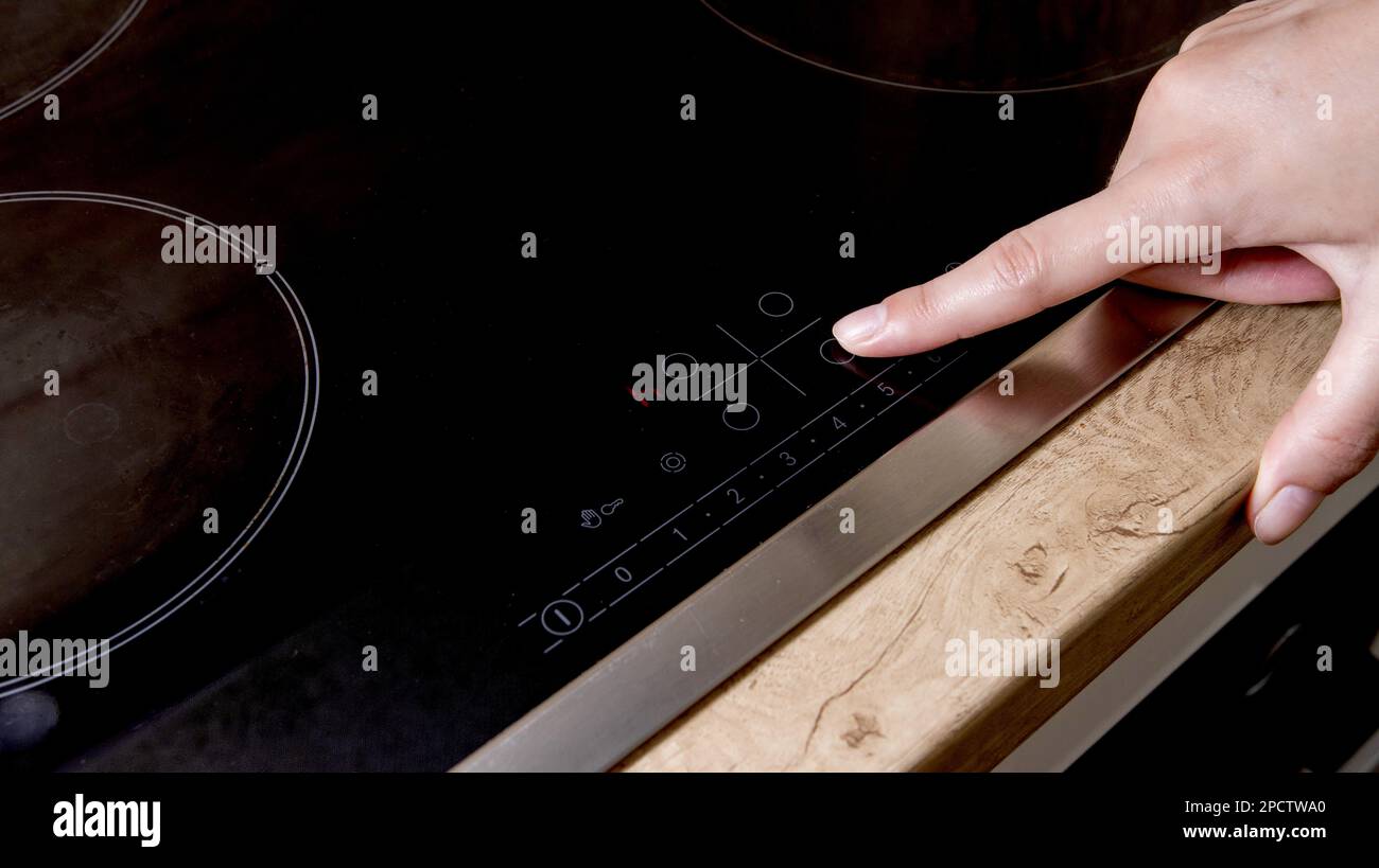 A woman's finger presses the inclusion of a modern induction hob in the ...