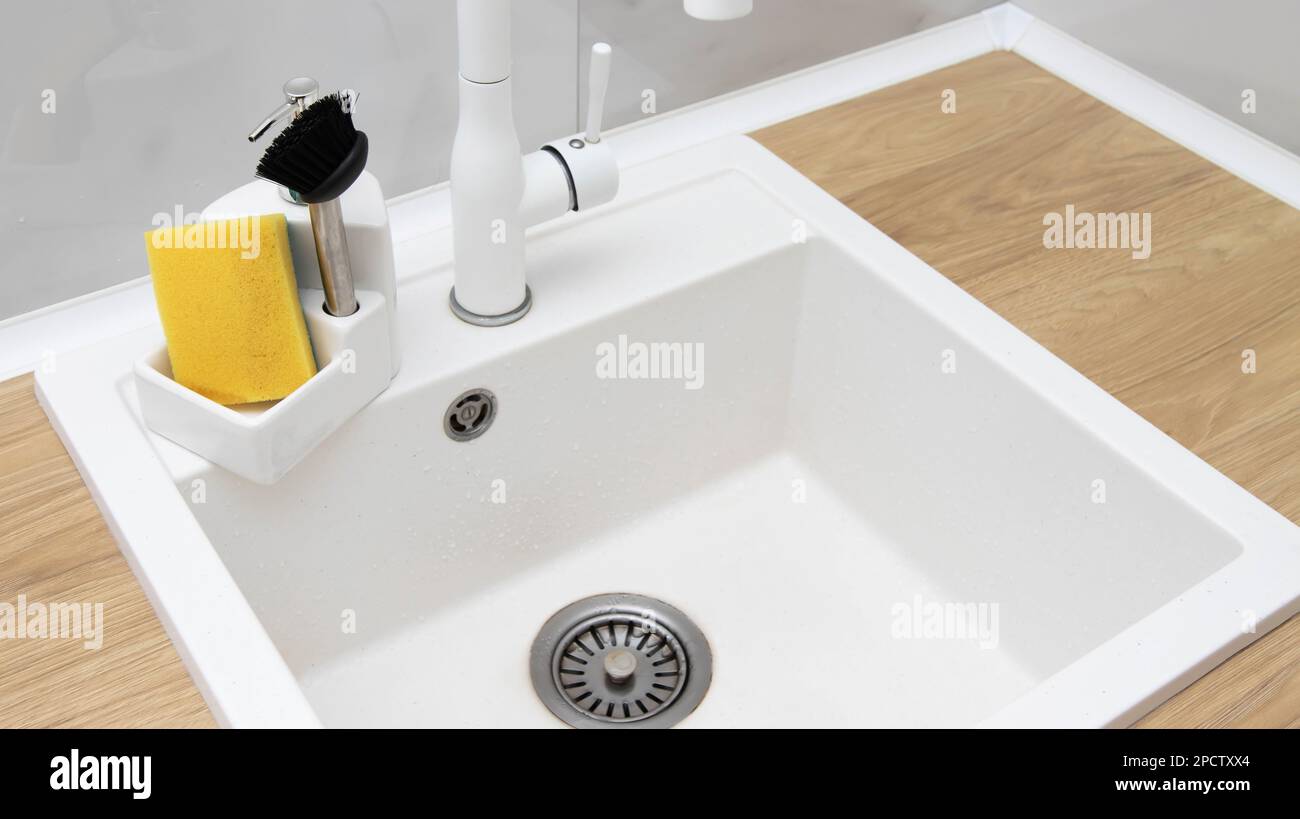 Beautiful kitchen interior of a white sink with a water faucet, sponge ...