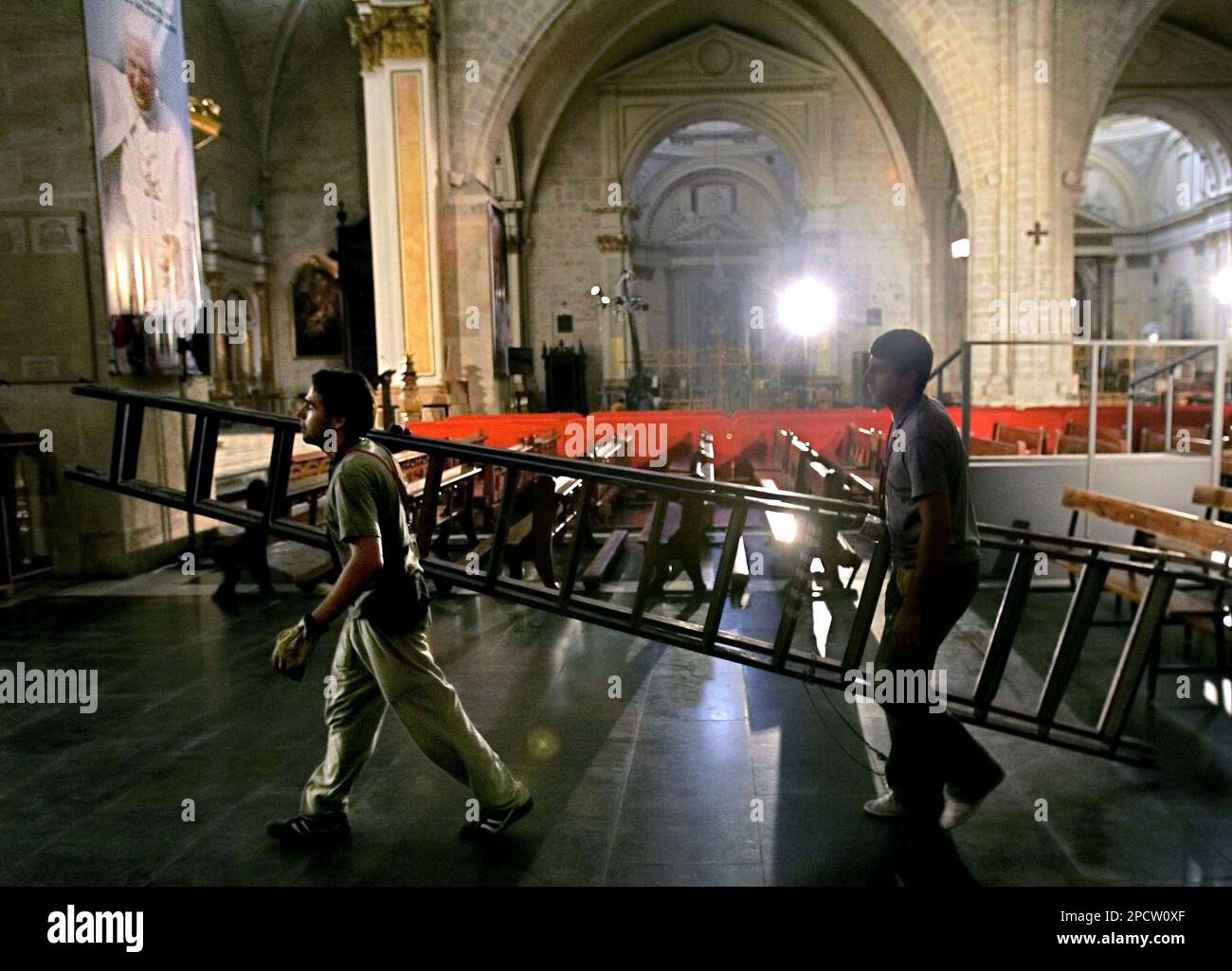 Workers carry a ladder in front of a poster depicting Pope Benedict XVI ...