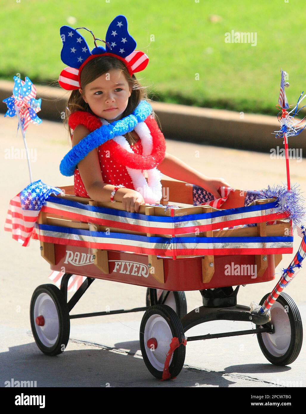 Audrey Richardson, 5, is pulled along the parade route by her parents ...