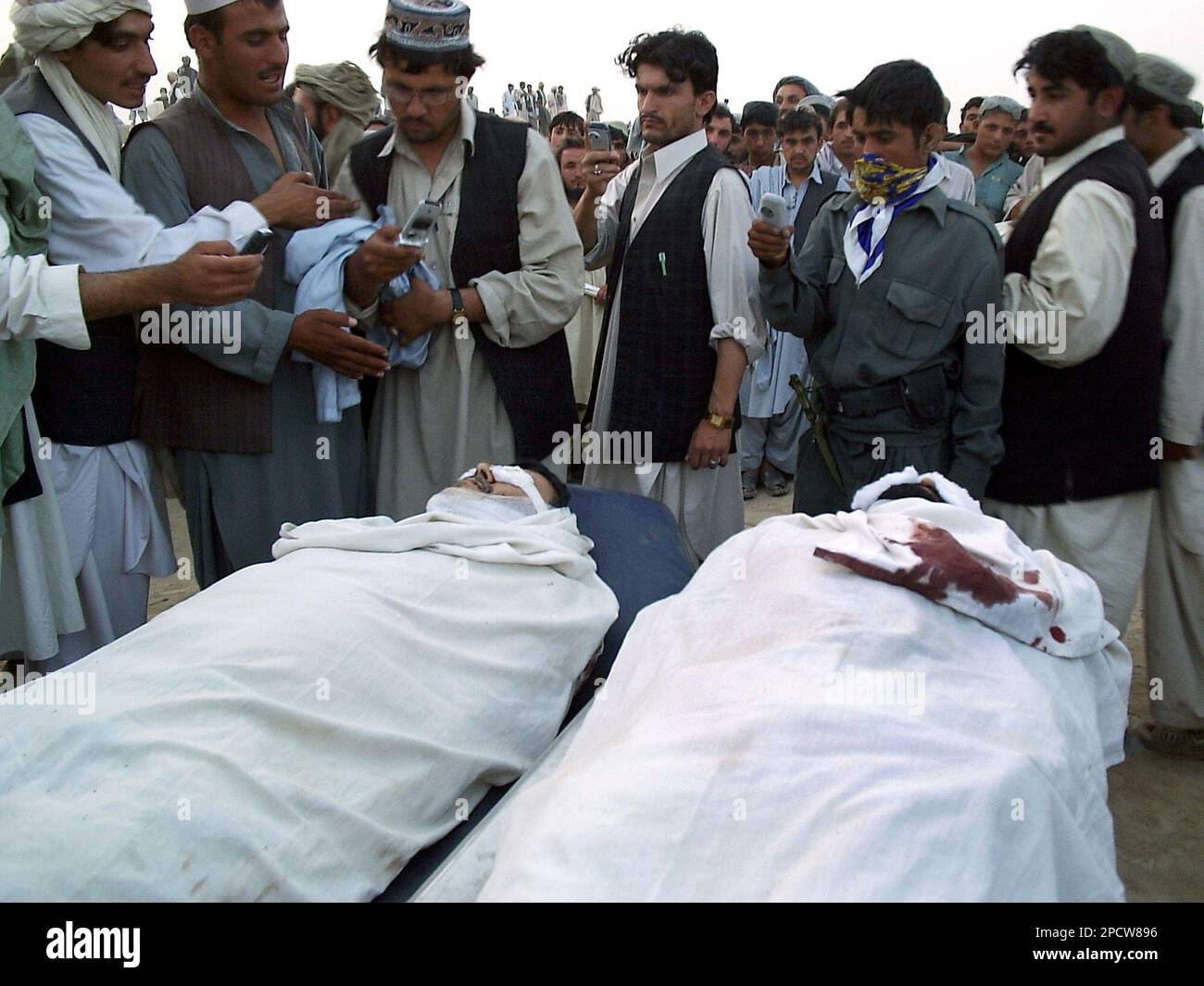 Pakistani mourners take the photos of the dead bodies of politician ...