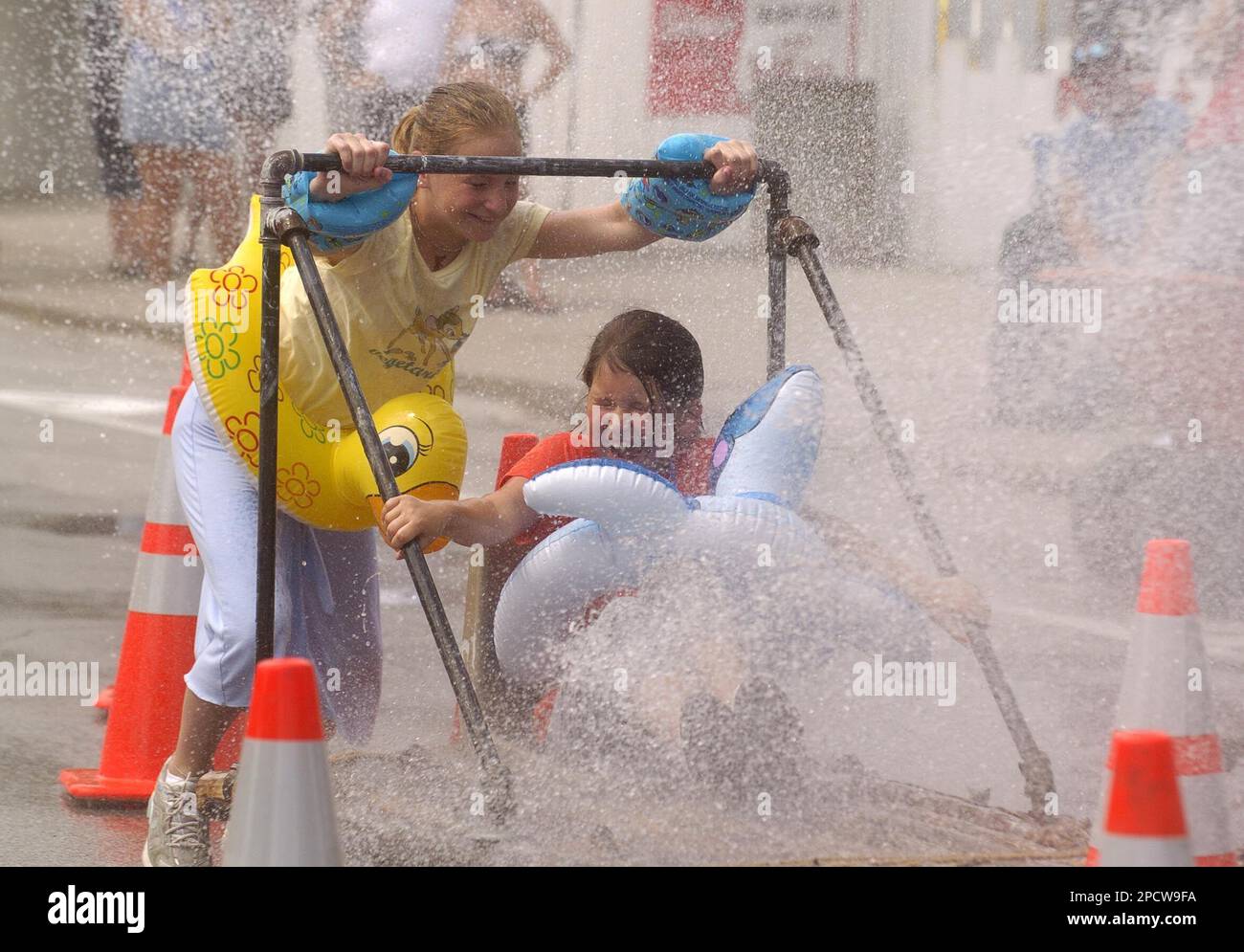 Michaela Lugena, 9, is sprayed with water as her best friend Stacie ...