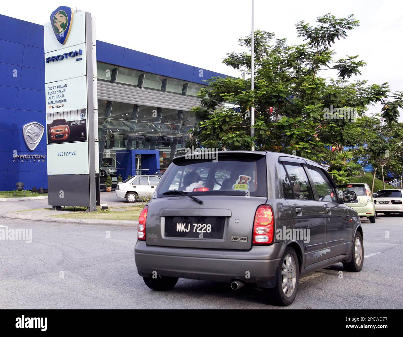 A Perodua compact car Kelisa drives past a Proton showroom in Kuala ...
