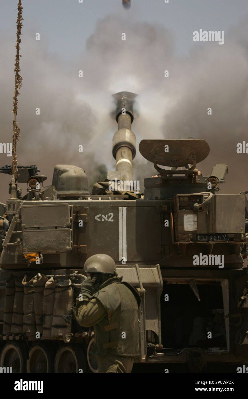 An Israeli soldier covers his ears as an Israeli mobile artillery piece ...