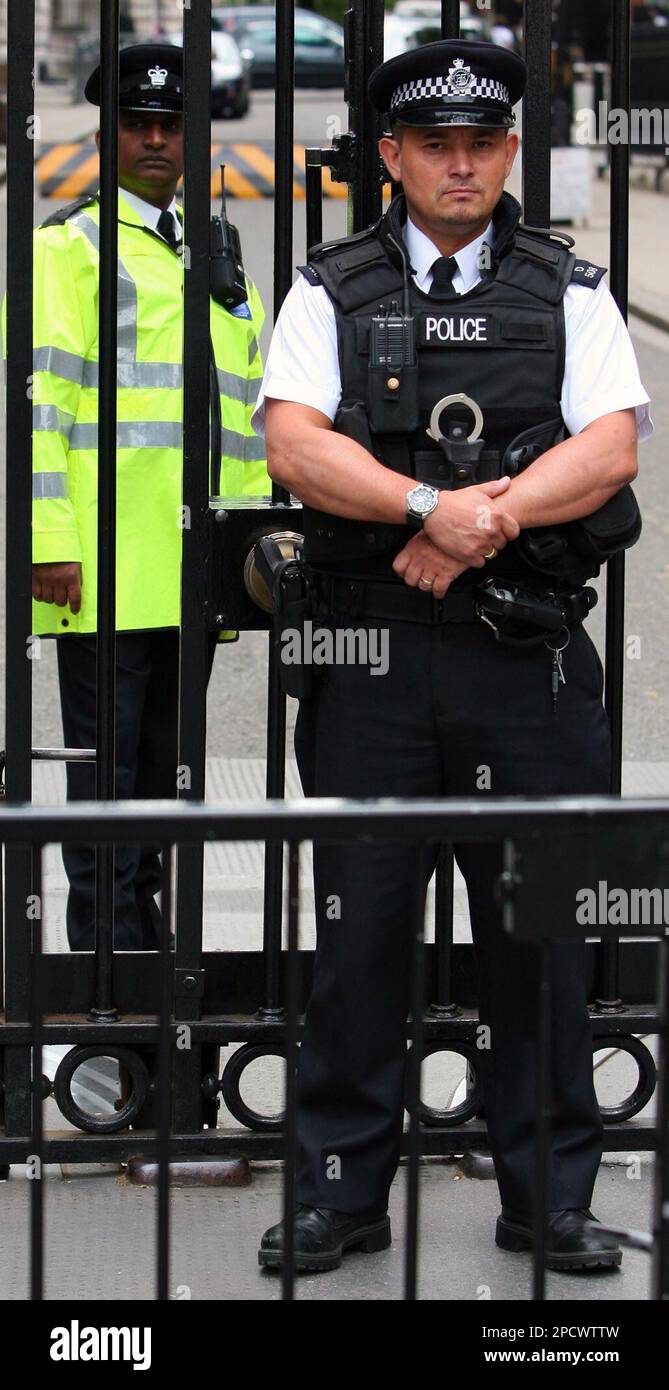An armed London Metropolitan police officer stands guard at the gates ...